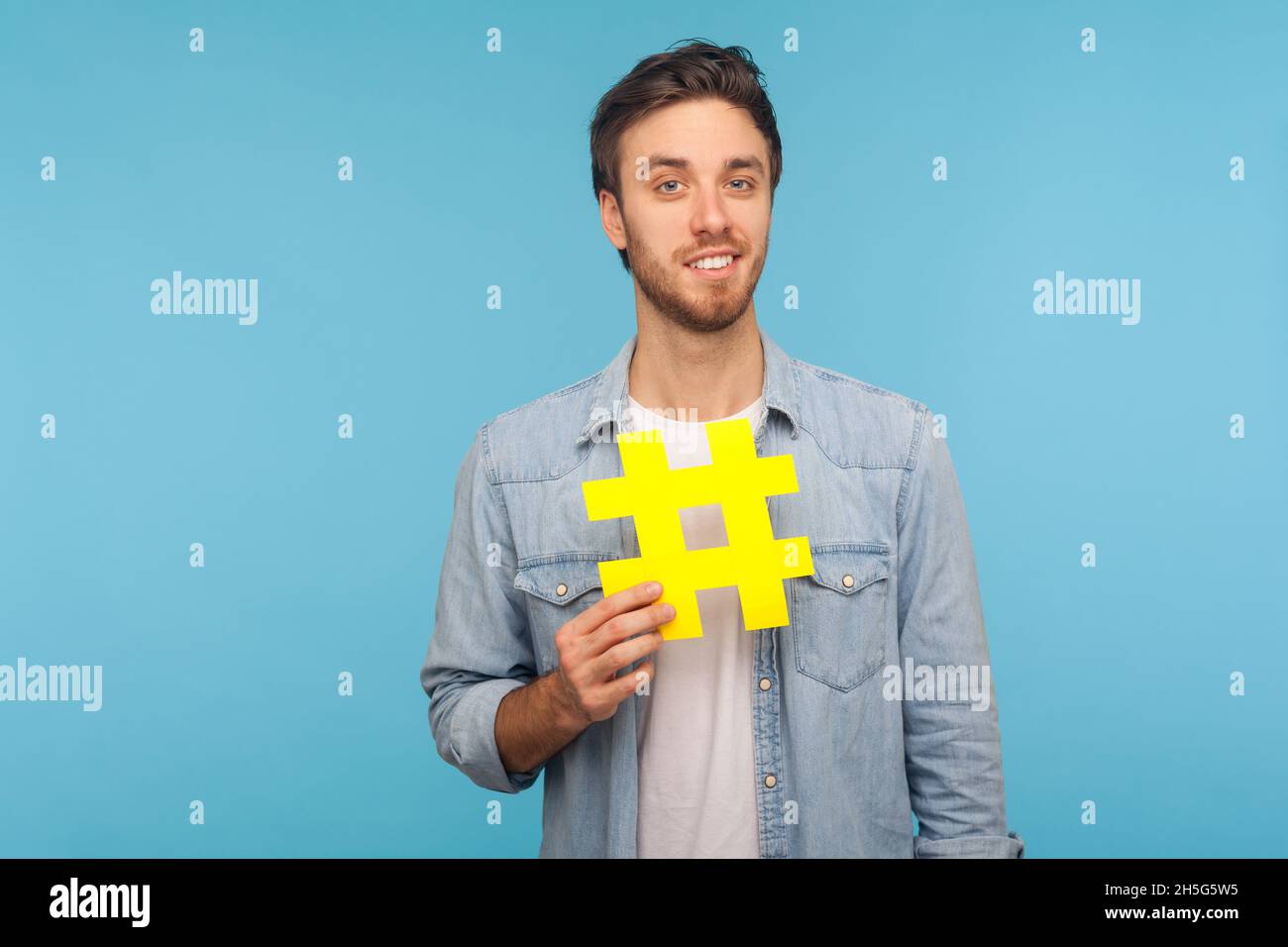 Portrait of smiling handsome man wearing denim shirt, holding large ...