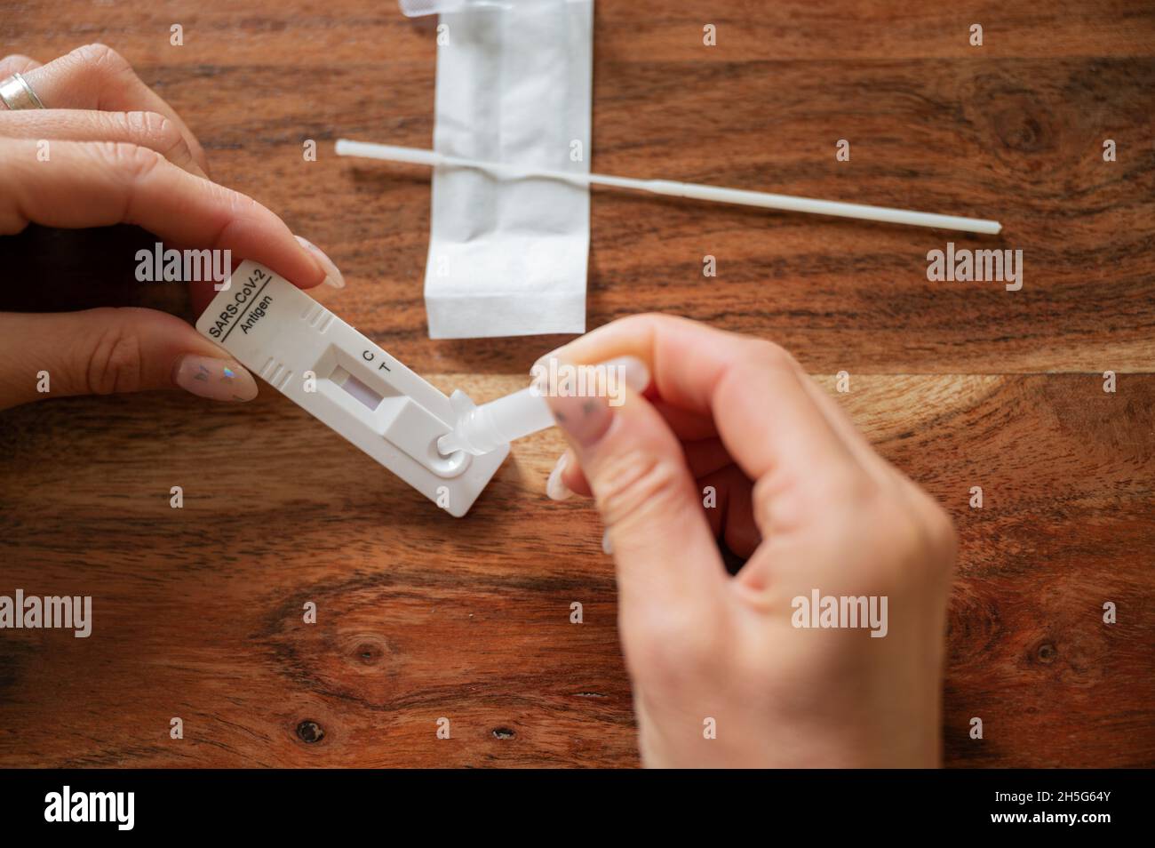 Top view of female hand dropping a solution of covid19 home self test ...