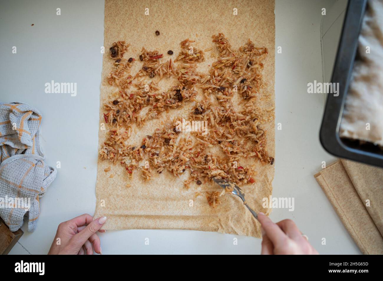 Top view of a woman making homemade vegan apple strudel with raisins on ...