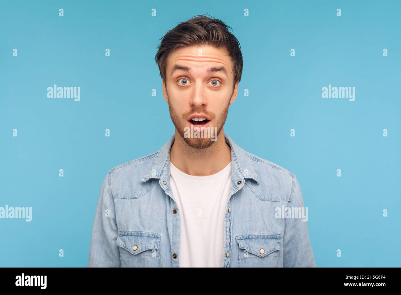 Portrait of astonished man wearing denim shirt, standing with mouth ...