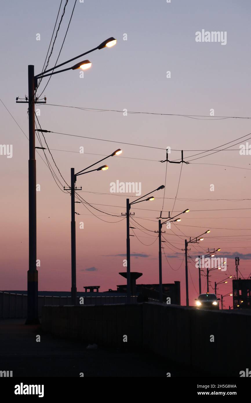 Vertical shot of the street lighting over the traffic road at sunset ...