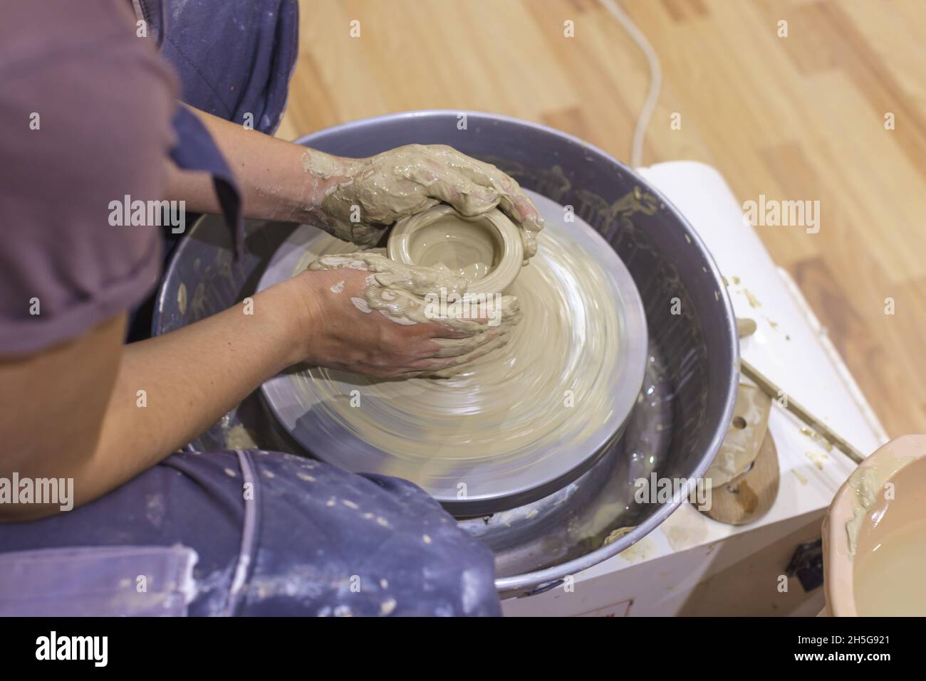 Female pottery artist shapes the clay on pottery wheel. Creative ...