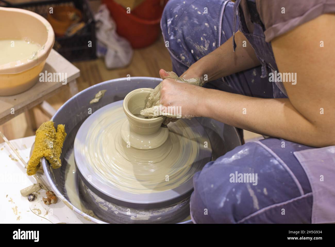 Female pottery artist shapes the clay on pottery wheel. Creative ...