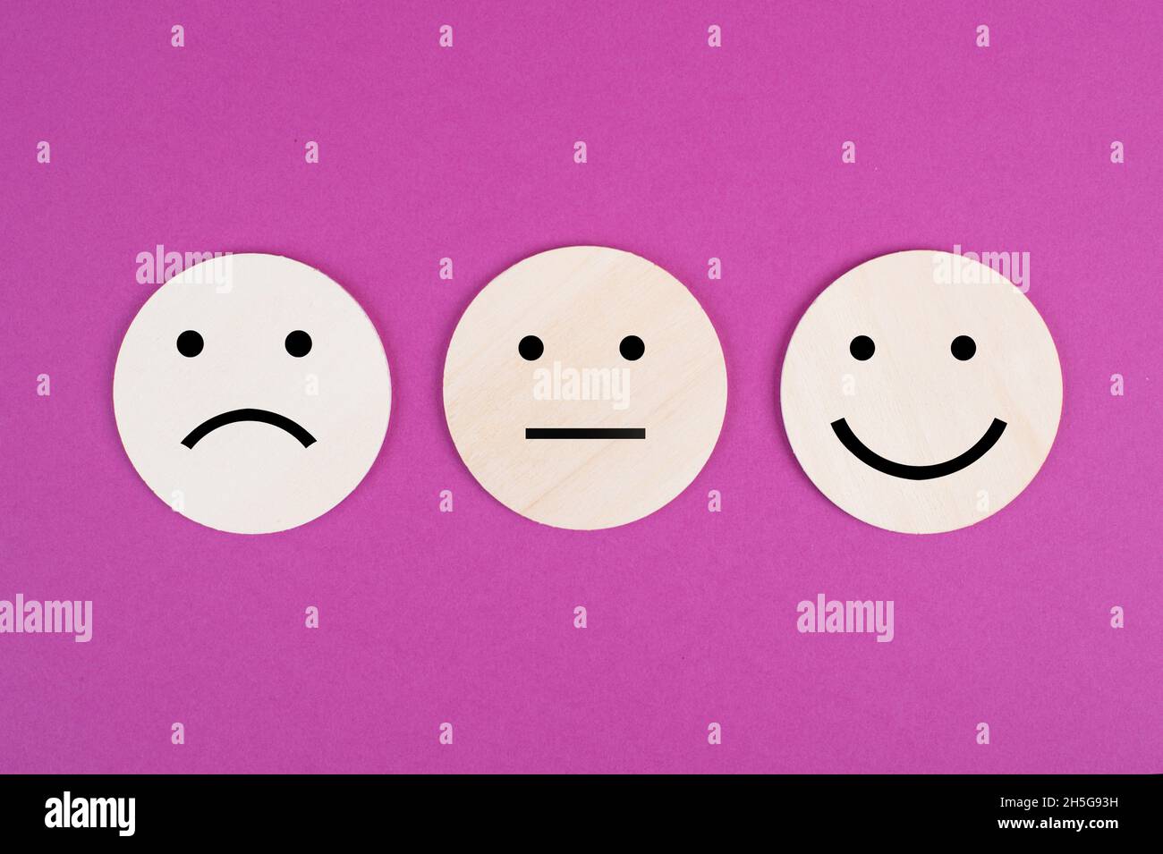 Three faces, smiling, sad in different colors on a pink background ...
