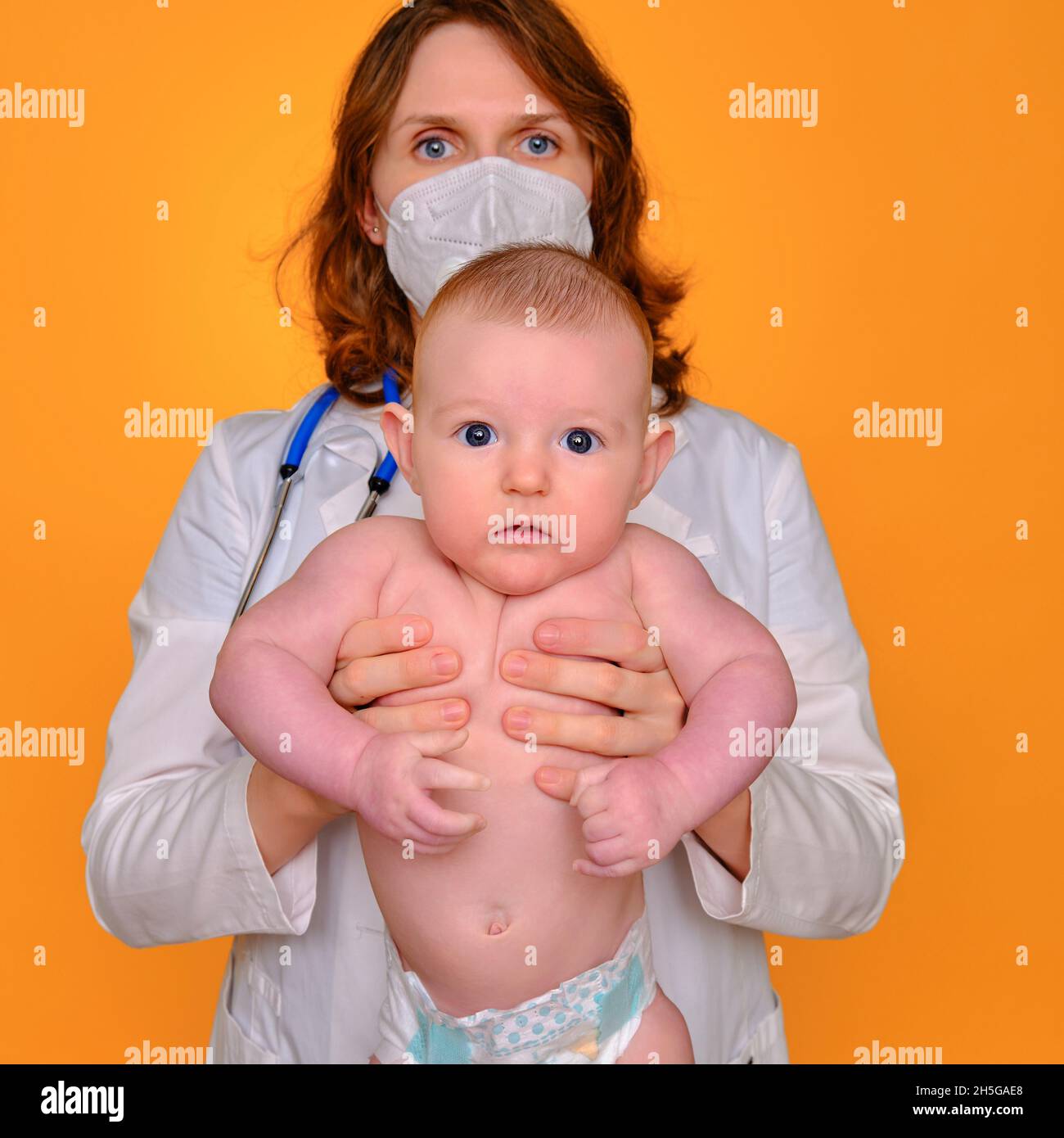 Woman pediatrician holding an infant baby in a diaper in her hands ...