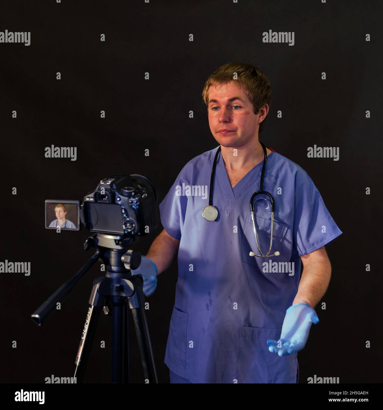 Sad paramedic records video story on camera, dark background Stock ...