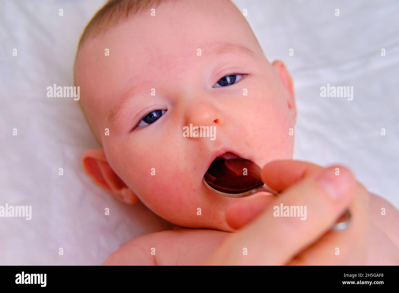 The mother gives the medicine Infant baby in the mouth on a spoon, oral ...