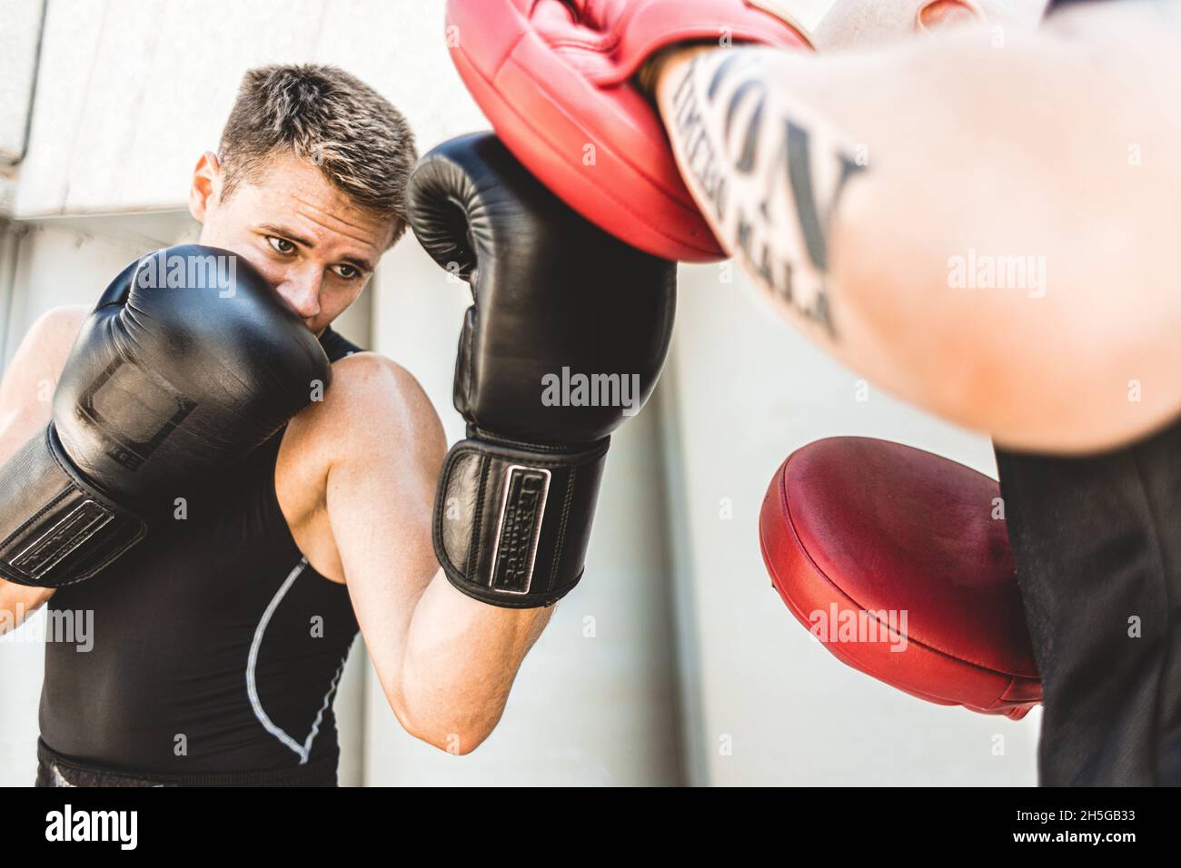 Two men exercising and fighting in outside. Boxer in gloves is training ...