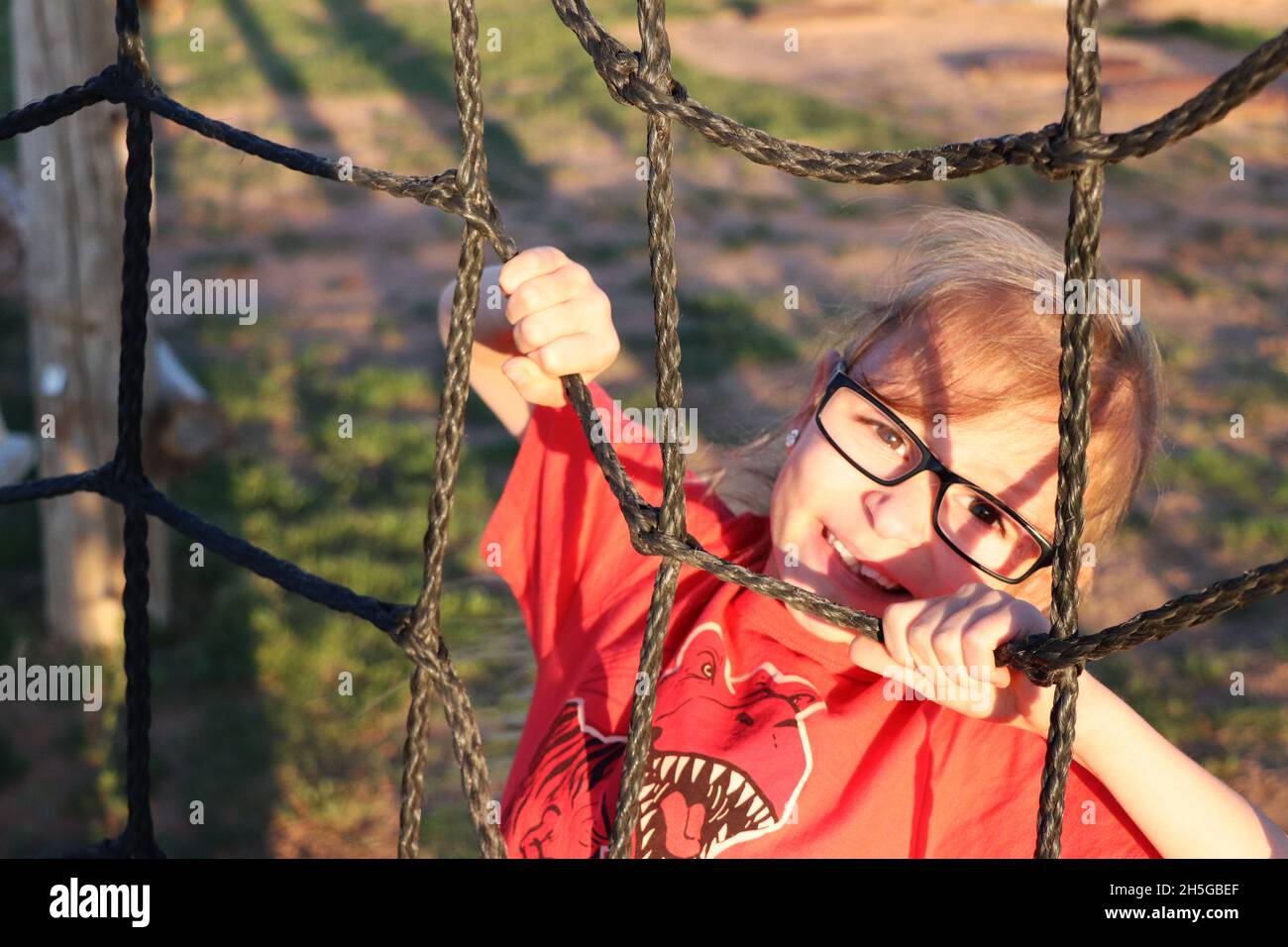 Child climbing on rope net at playground Stock Photo - Alamy