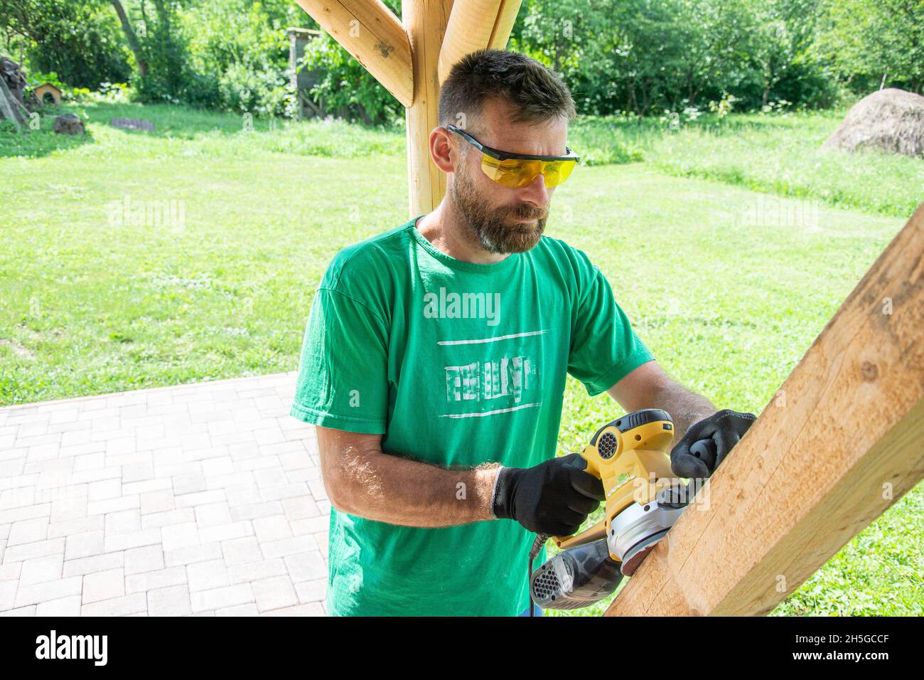Worker grinds the wood of angular grinding machine at his workstation ...