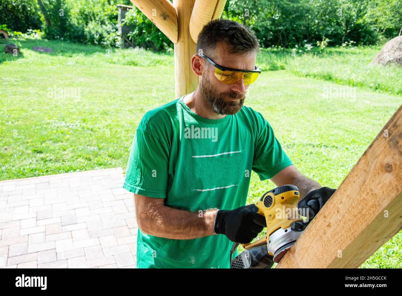Worker grinds the wood of angular grinding machine at his workstation ...