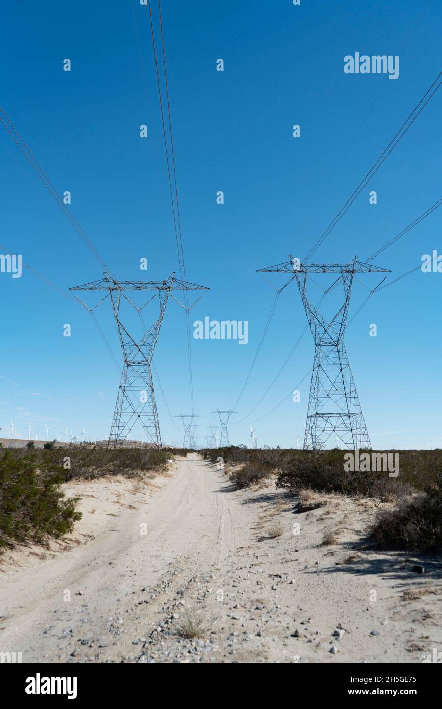 A dirt road following between the path to two high tension power towers ...