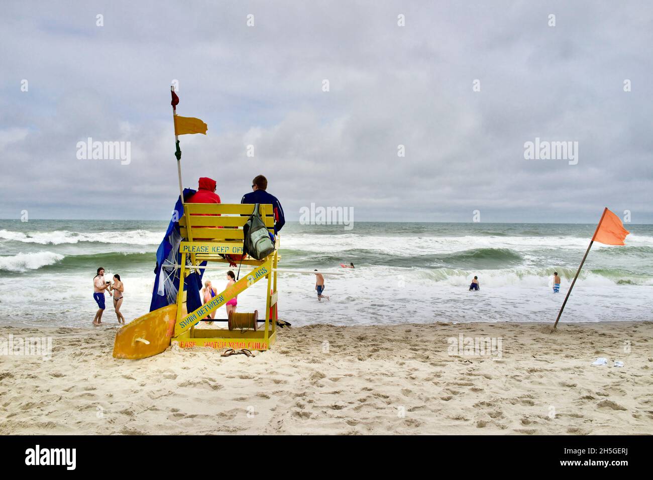 Two Lifeguards sit in high wooden beach chair watching swimmers on the ...