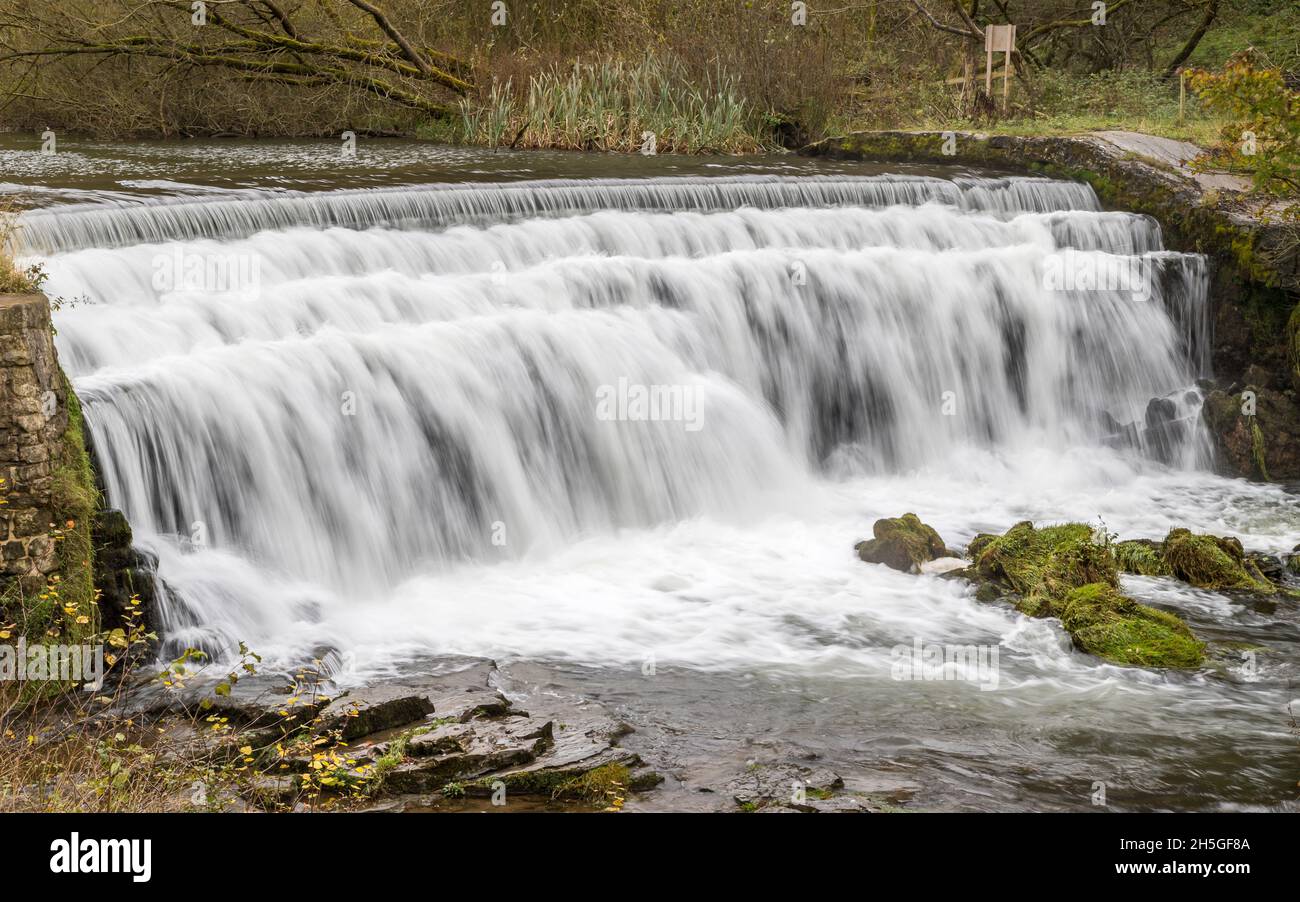 A large curved weir seen down the River Wye near to Monsal Head seen in ...