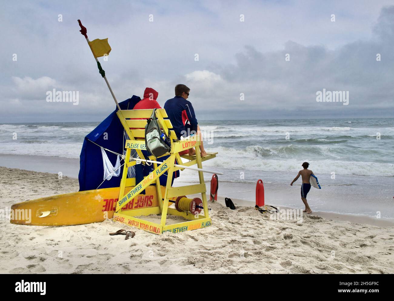 Two Lifeguards sit in high wooden beach chair watching swimmers on the ...