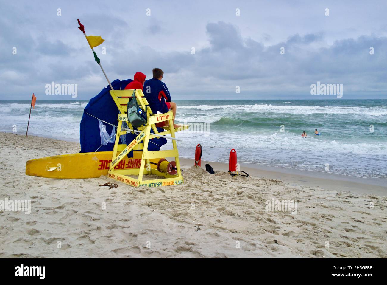 Two Lifeguards sit in high wooden beach chair watching swimmers on the ...