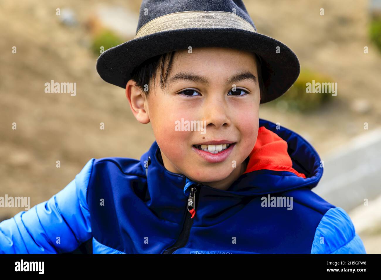 A Young Inuit boy wearing a hat in the Village of Tasiilaq looks at the ...