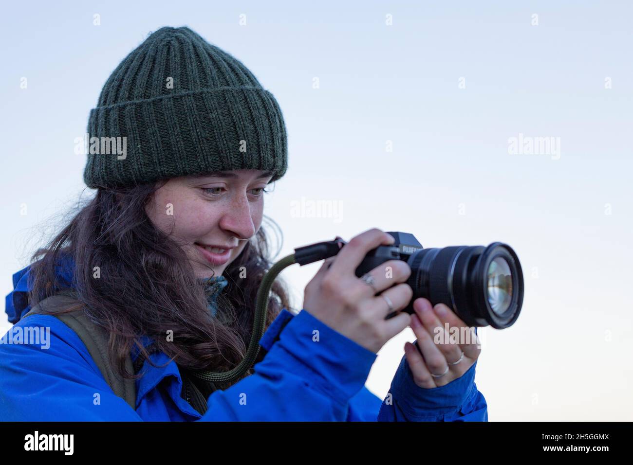 Young woman photographing the outdoors with digital camera and lens in ...
