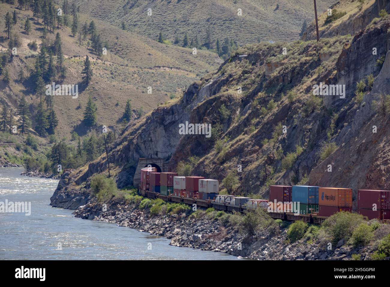 A transport train with colourful shipping containers runs along the ...