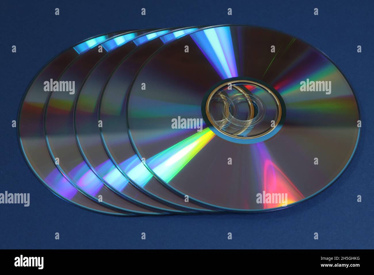 Five shiny compact CD and DVD discs on the dark blue surface Stock ...