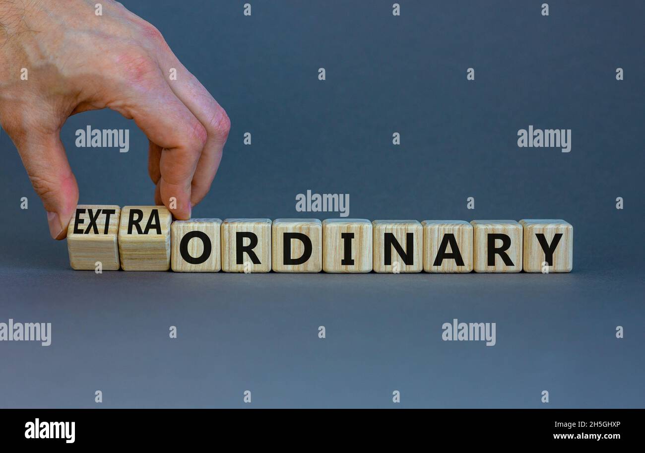 Ordinary or extraordinary symbol. Businessman turnes wooden cubes and ...