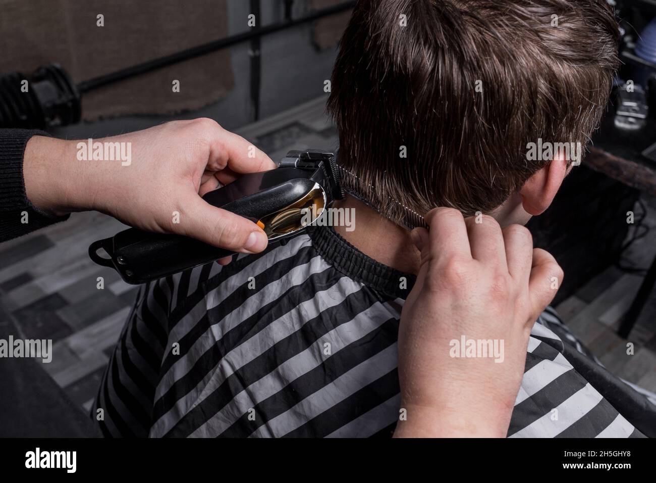 The hands of a barber or hairdresser cut the back of the client's head ...