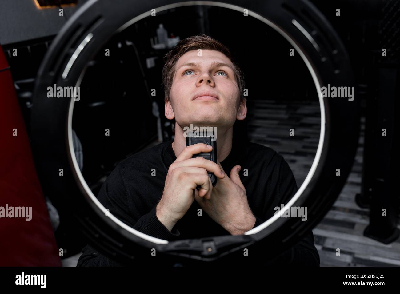 A serious young guy of Caucasian appearance with dark hair shaves with ...