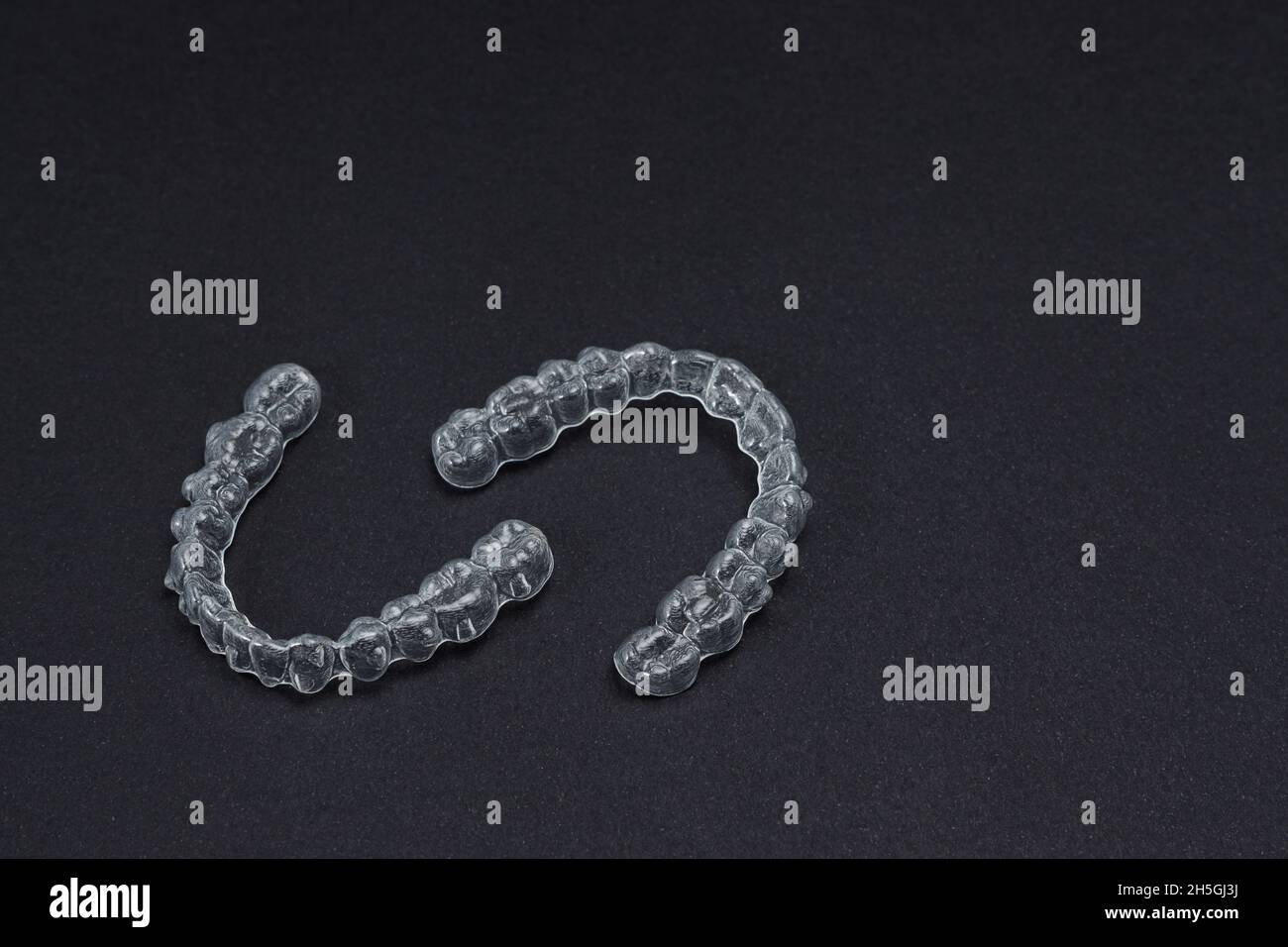 Two transparent retainers on black background. Invisalign orthodontics ...