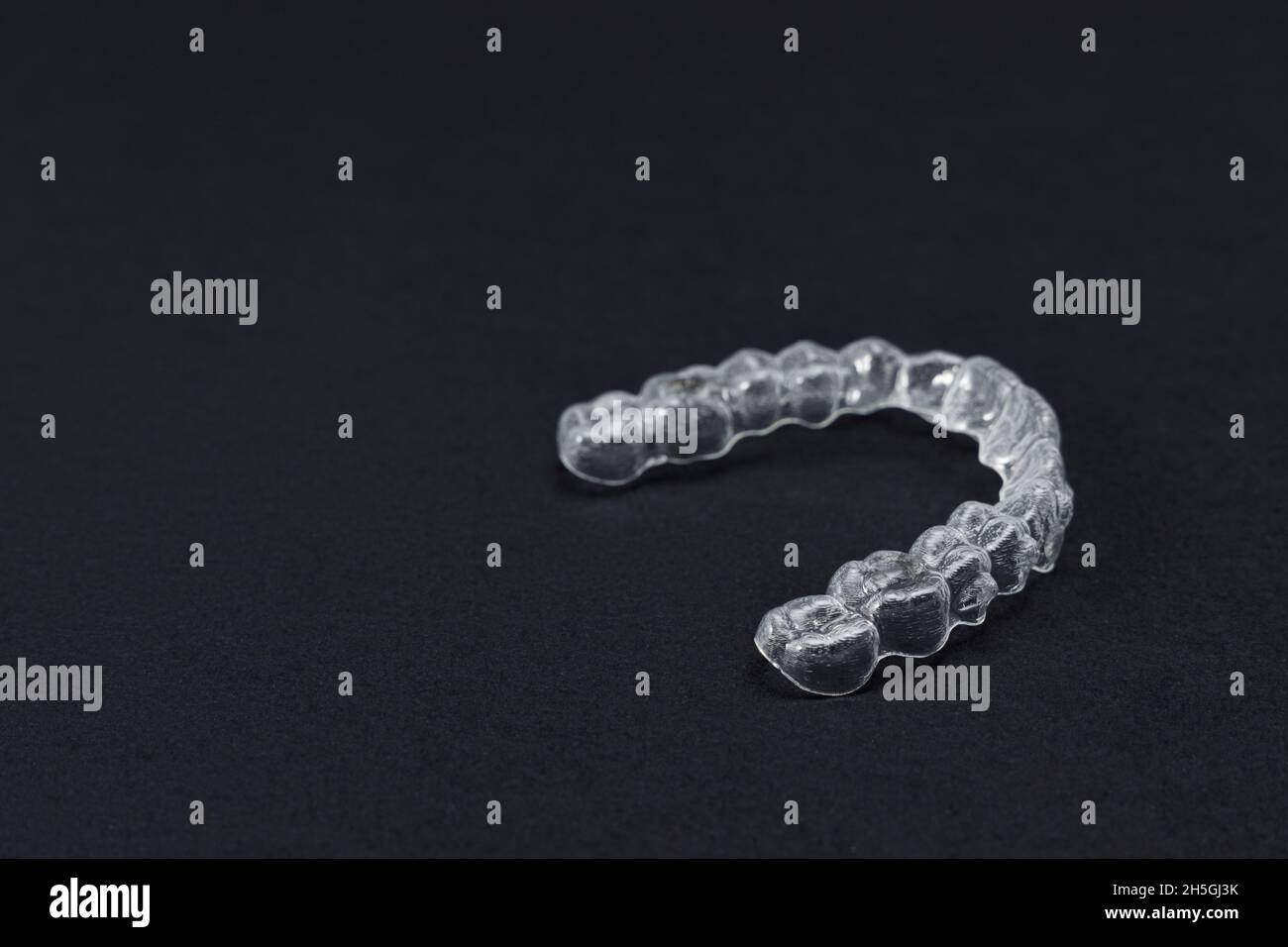 One transparent retainer on black background. Invisalign orthodontics ...