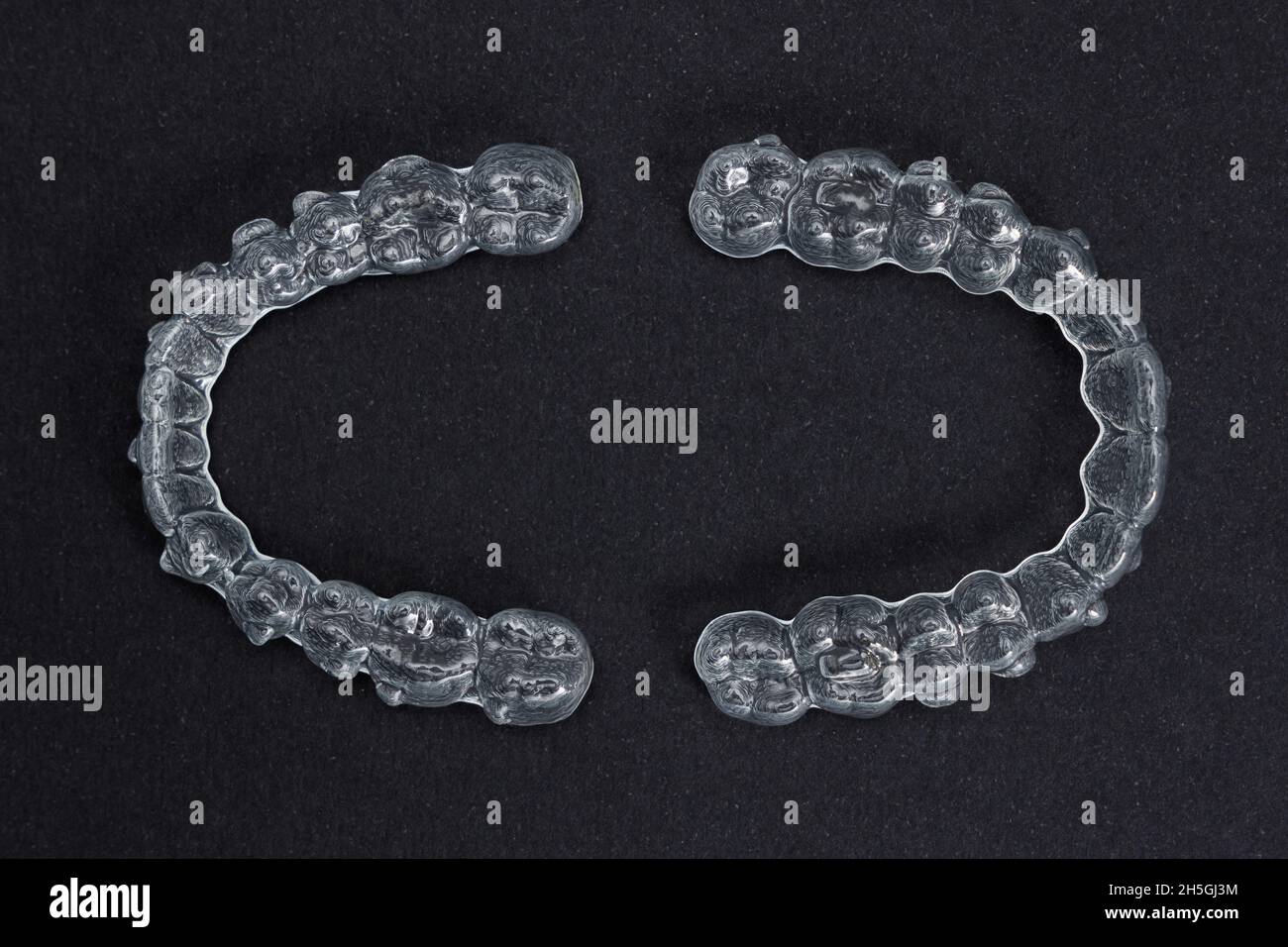 Two transparent retainers on black background. Invisalign orthodontics ...