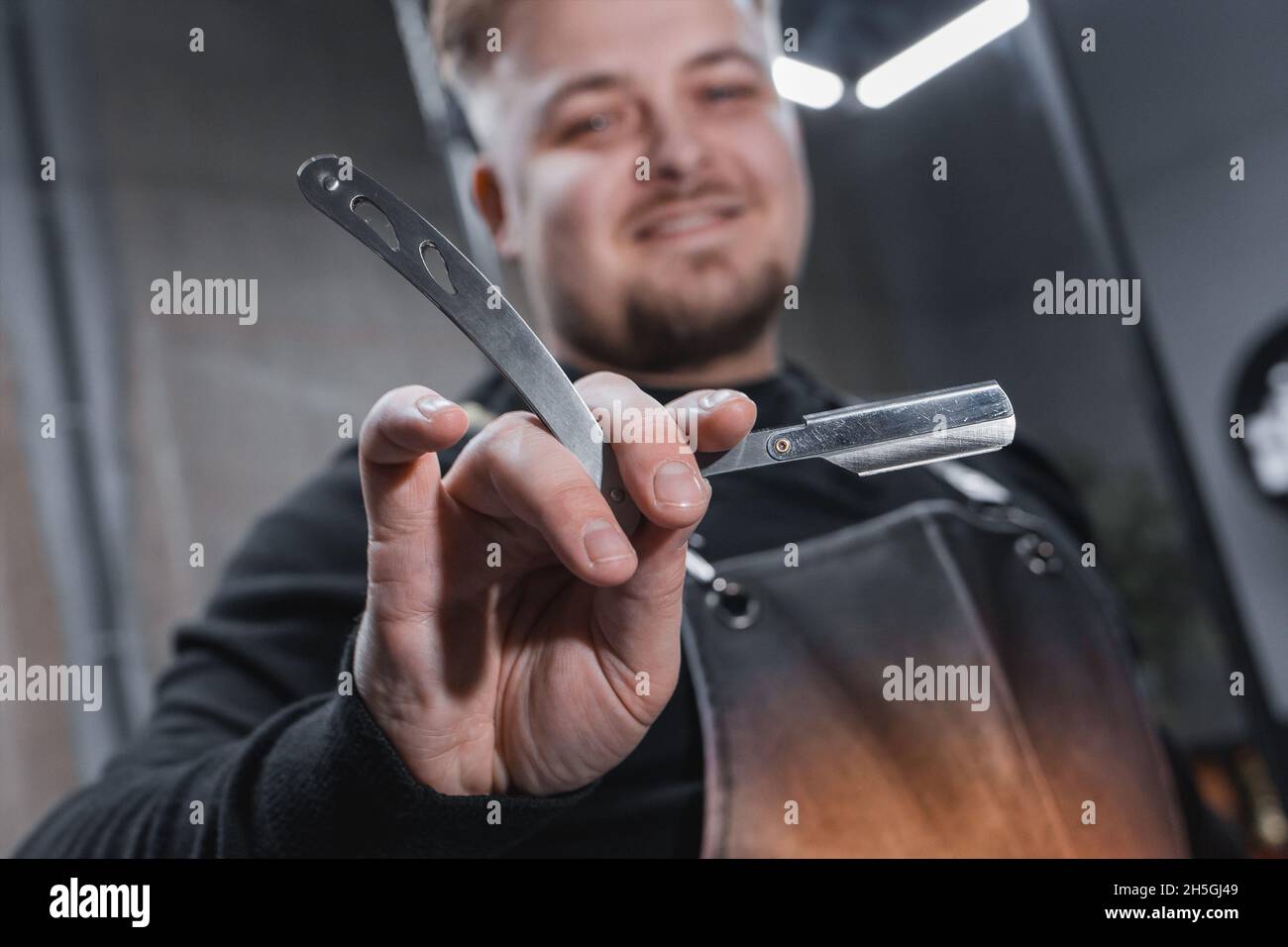 The hand of a barber or professional hairdresser holds a straight tool ...