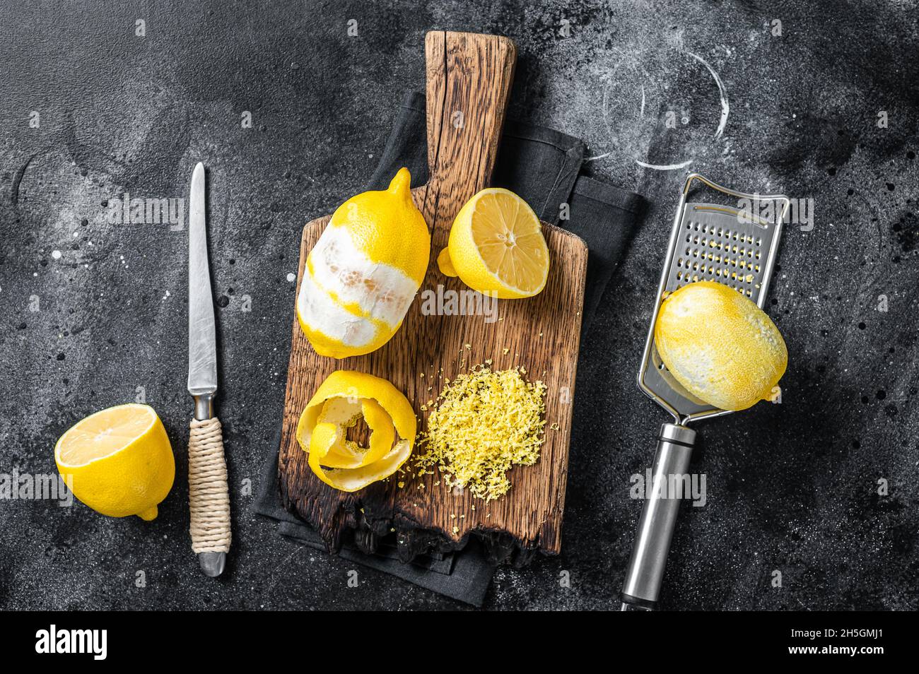 Grated Lemon Zest and spiral peel on wooden board. Black background ...