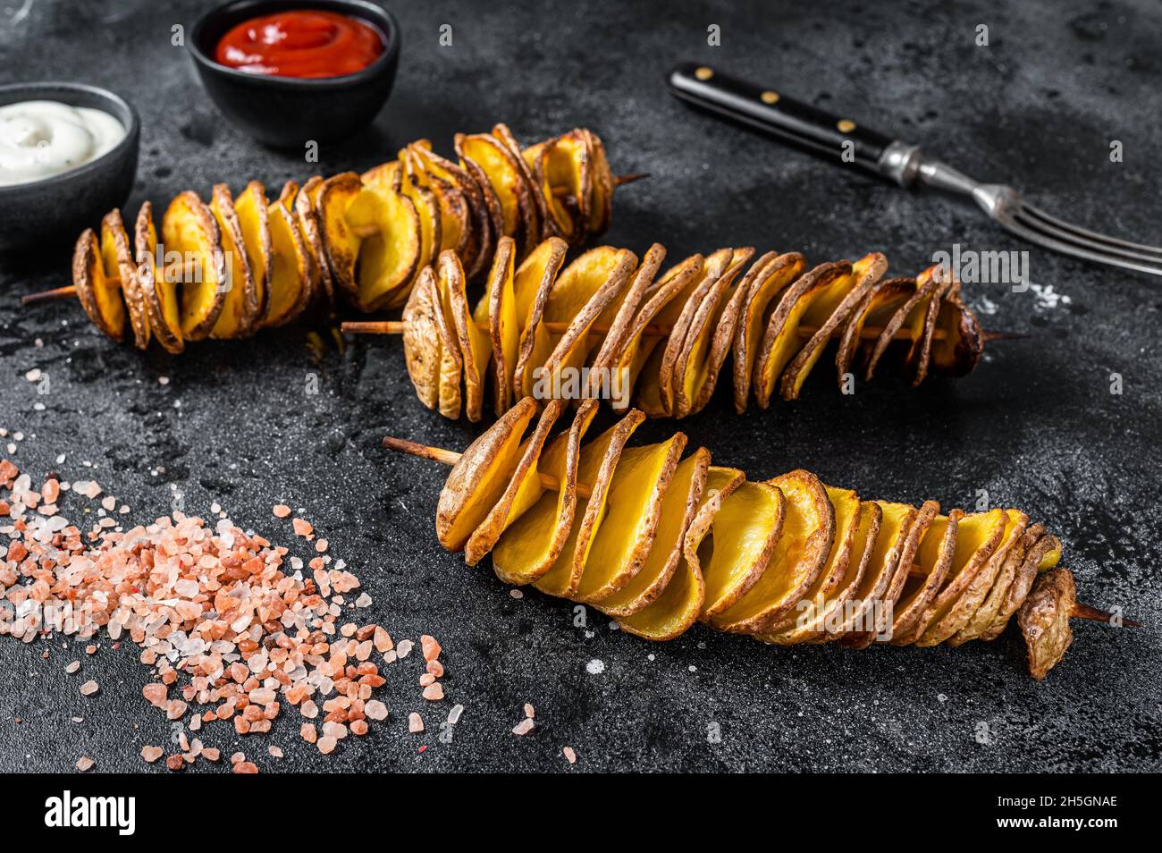 Roasted Tornado or twisted potatoes with ketchup sauce. Black ...