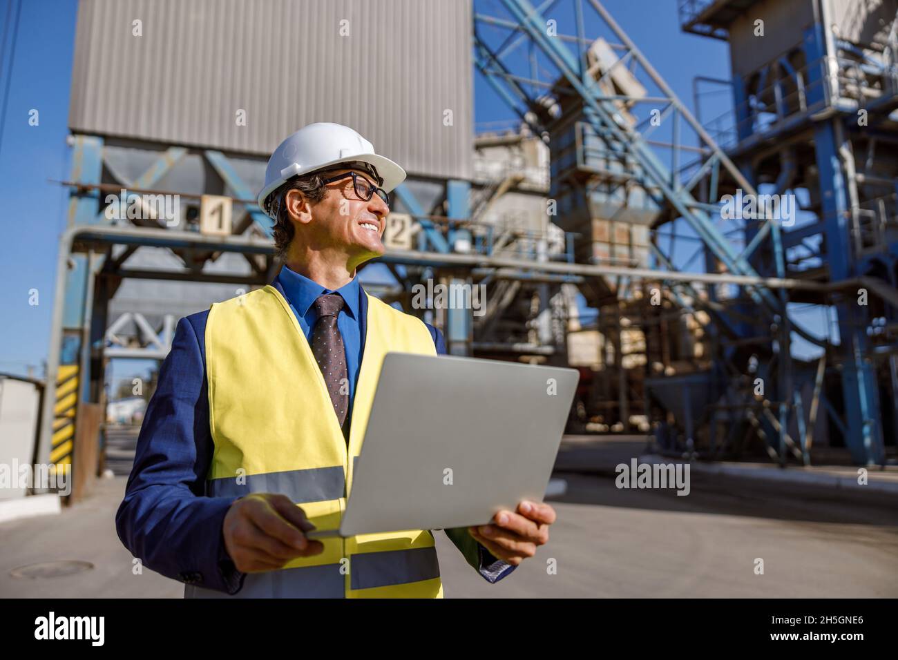 Cheerful male engineer using notebook outdoors at factory Stock Photo ...