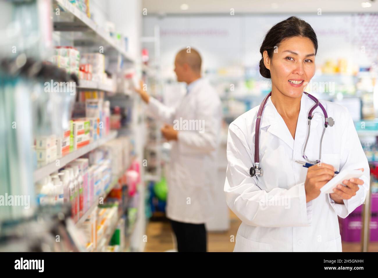 Positive female pharmacist writes in a notebook in the trading floor of ...