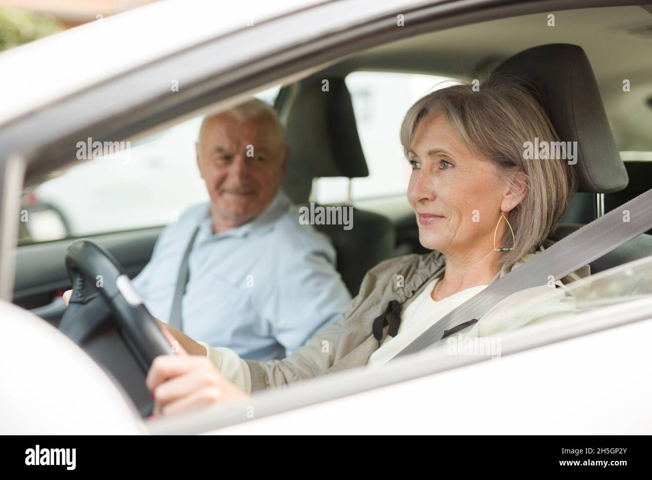Elderly married couple driving a car in the city. Woman driving car ...