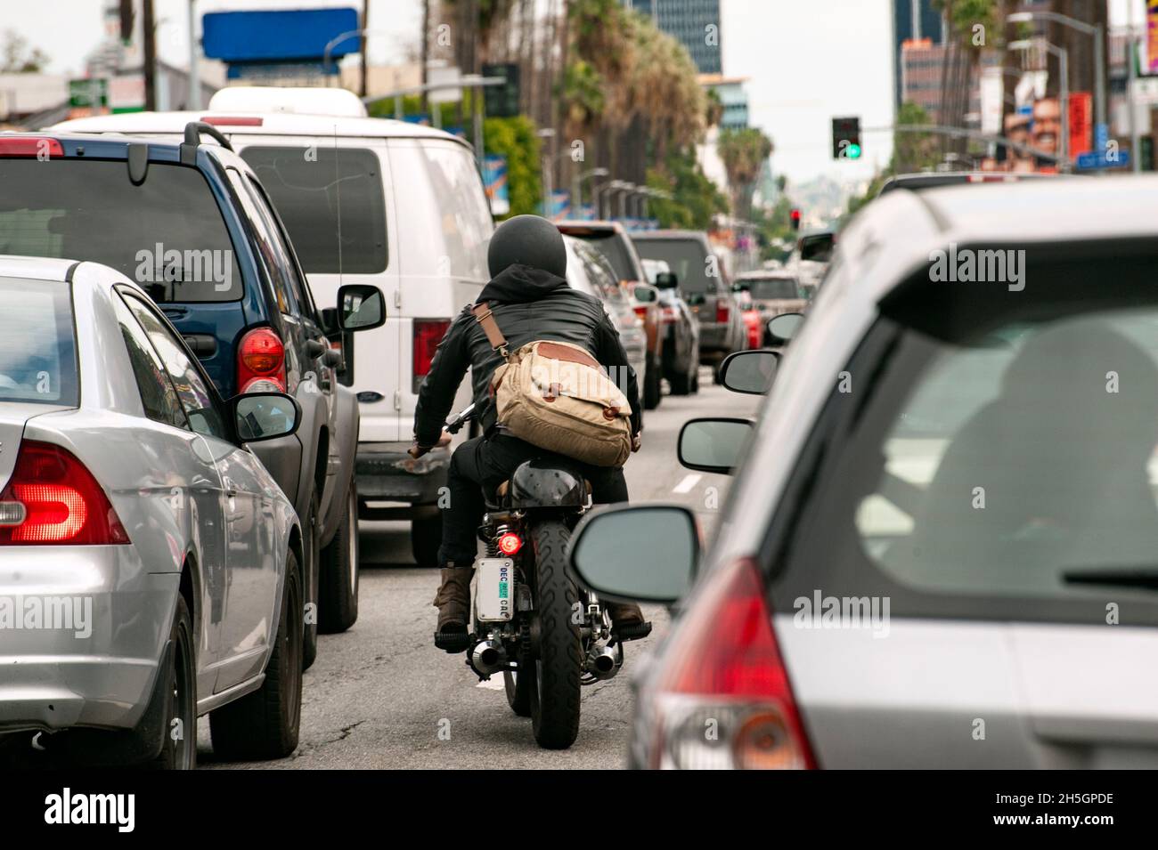 Motorcycle rider lane-splitting in heavy traffic Stock Photo - Alamy