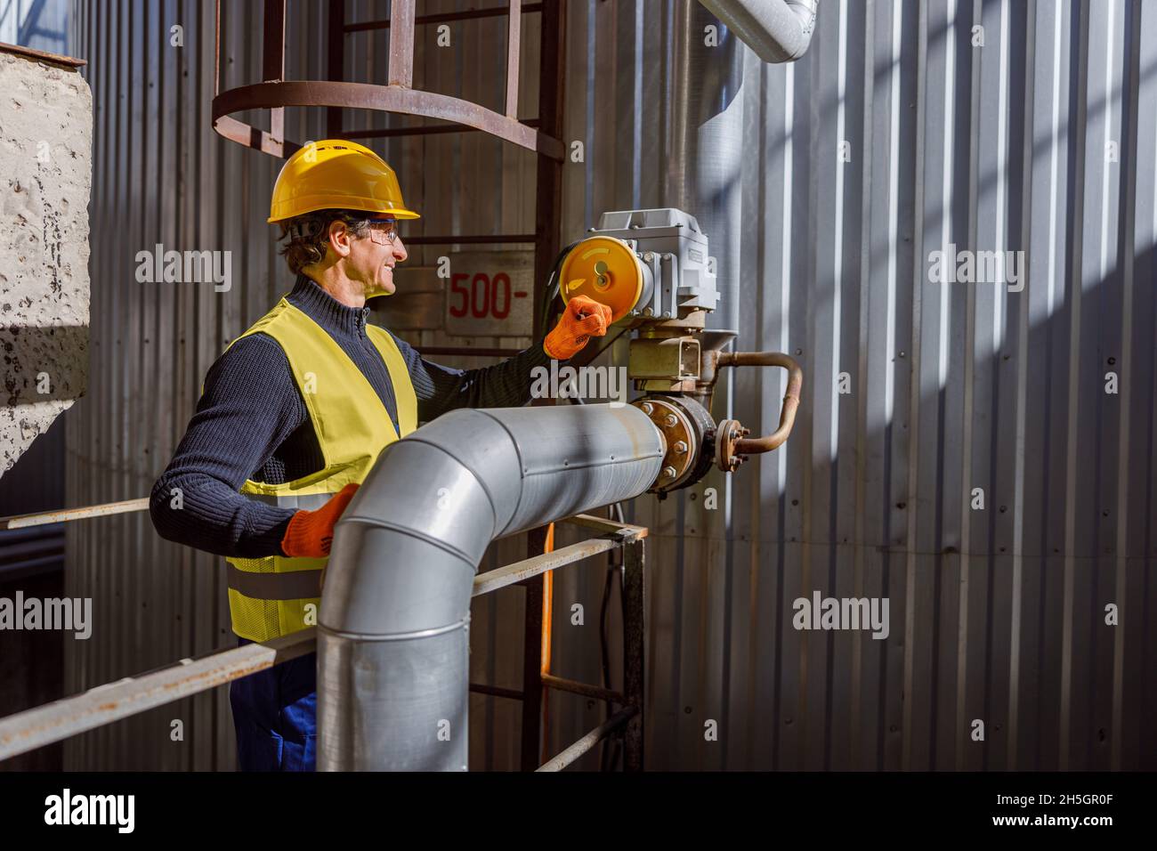 Joyful male engineer in safety helmet working at factory Stock Photo ...