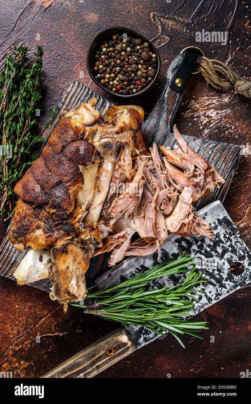Roasted and cut German pork knuckle eisbein meat on a wooden board with ...