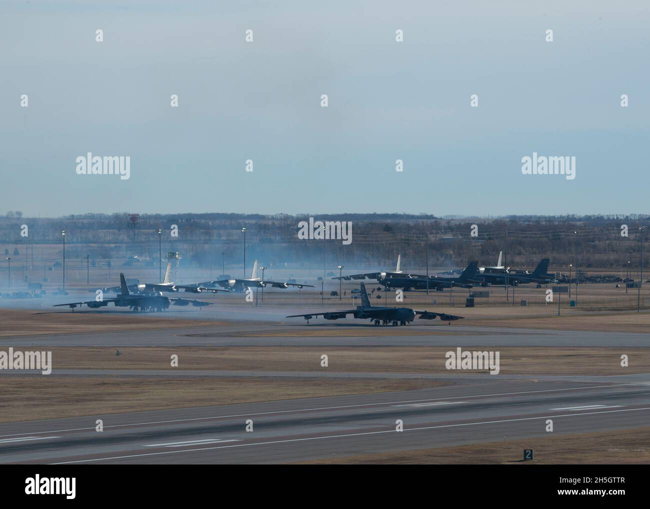 A line of B-52 Stratofortresses take off from the flightline at Minot ...