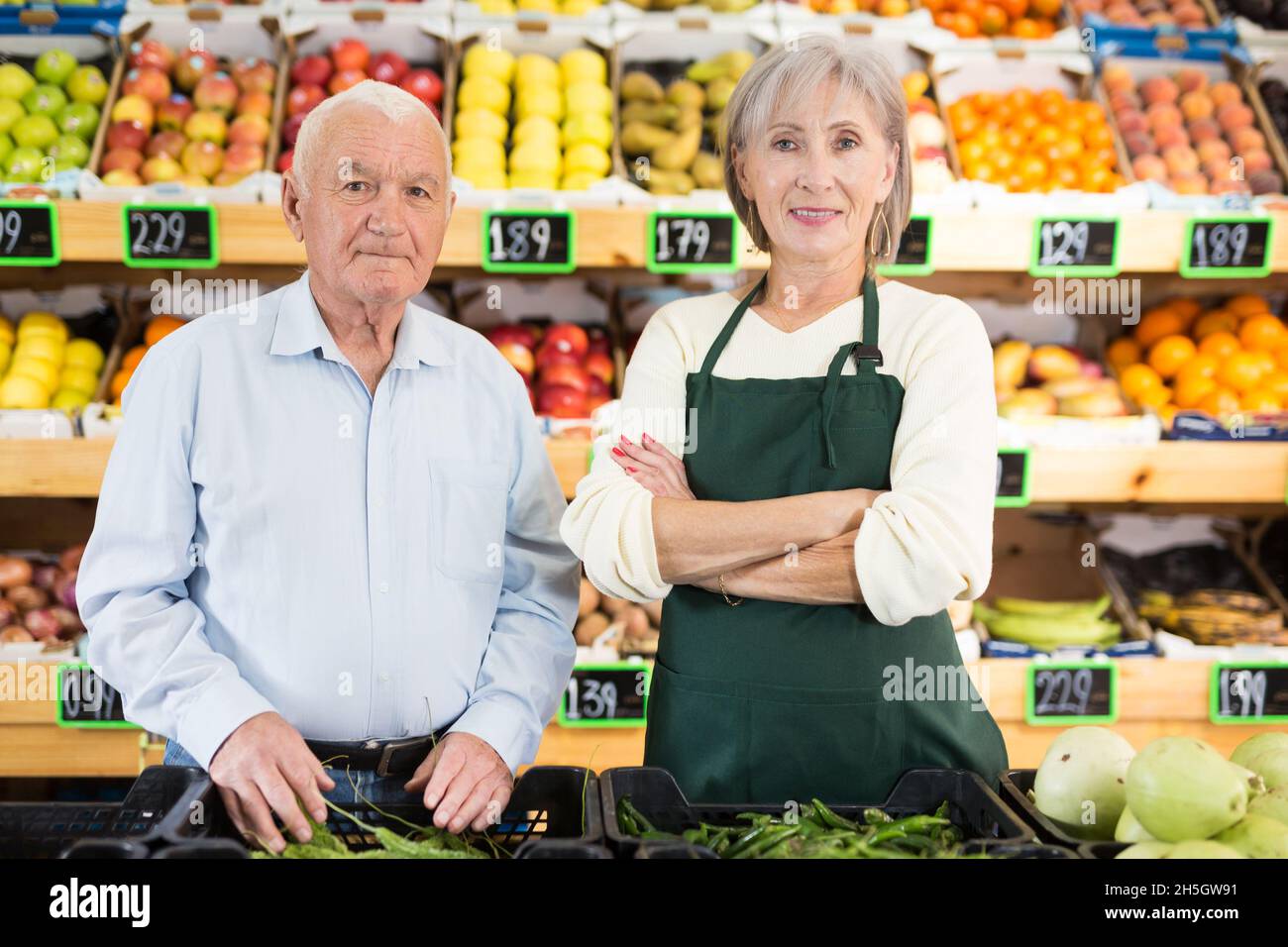 Mature supermarket worker and customer in salesroom Stock Photo - Alamy