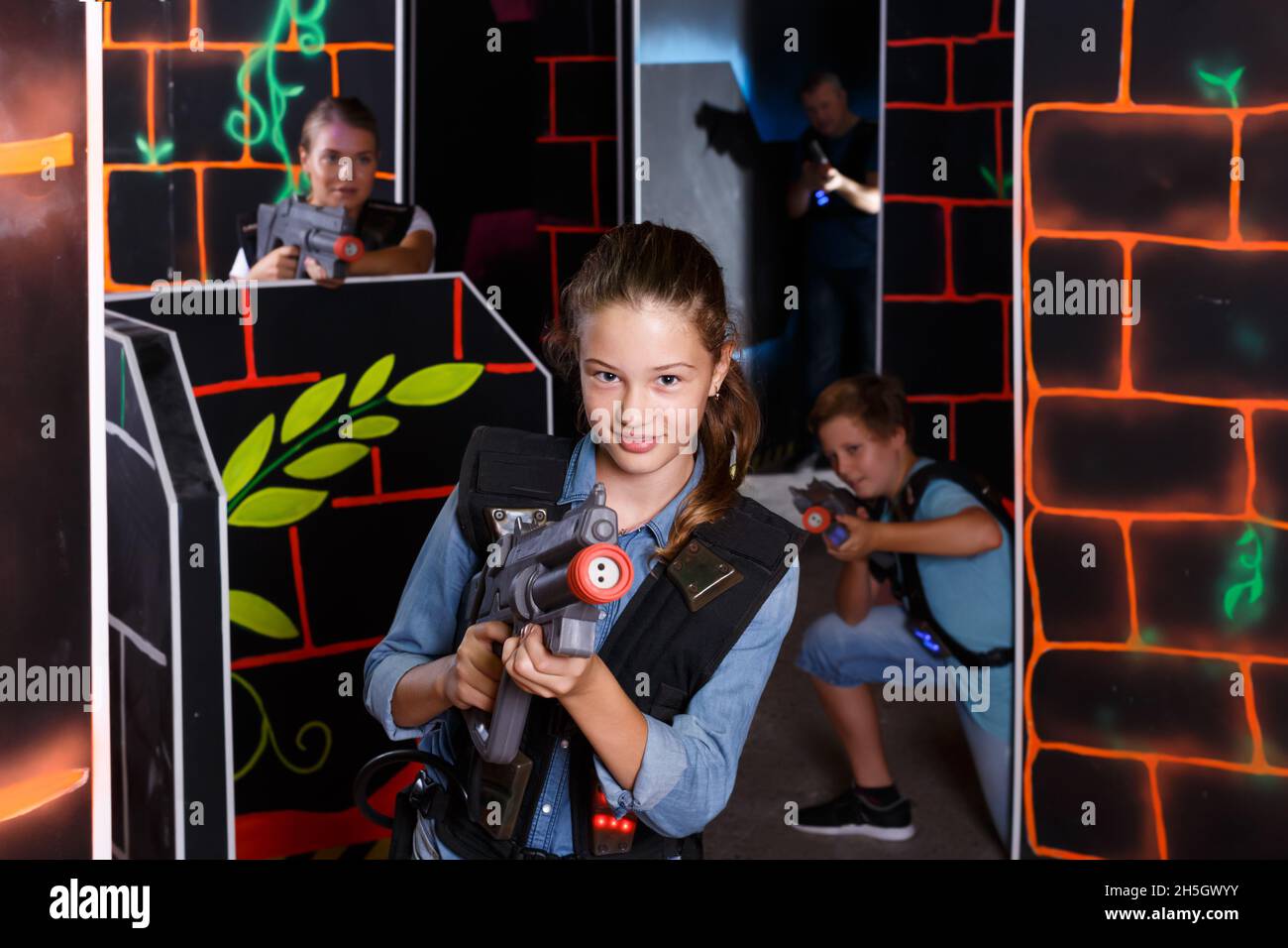 Positive girl aiming laser gun at other players Stock Photo - Alamy