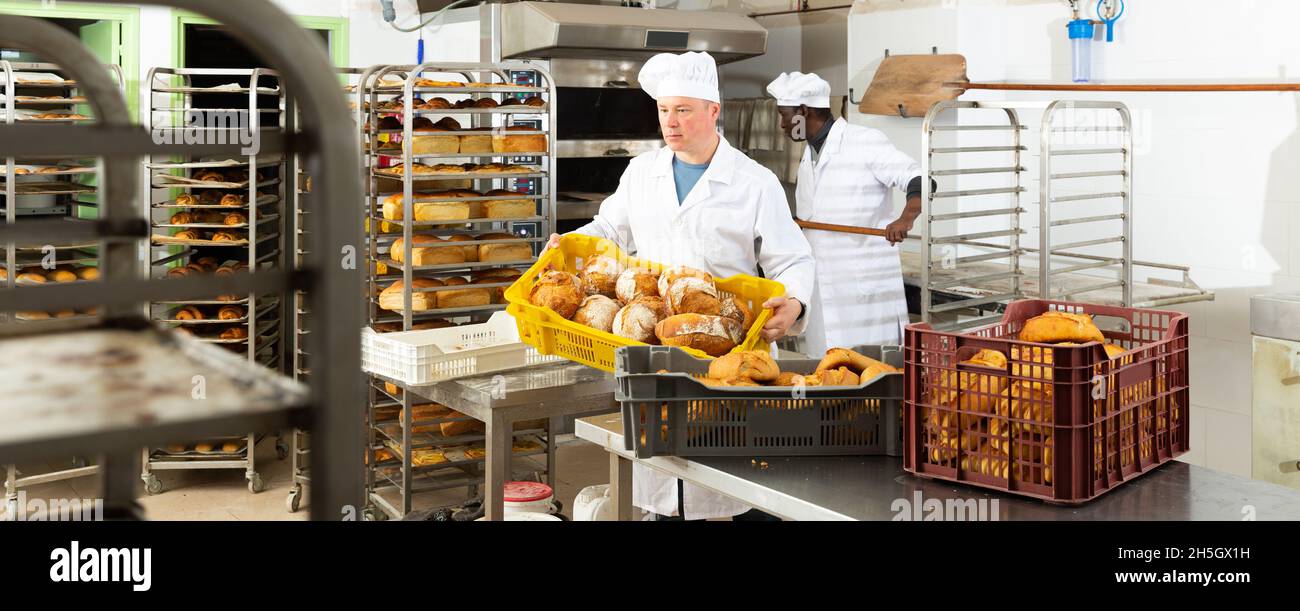 Two bakers arranging baked bread in bakery Stock Photo - Alamy