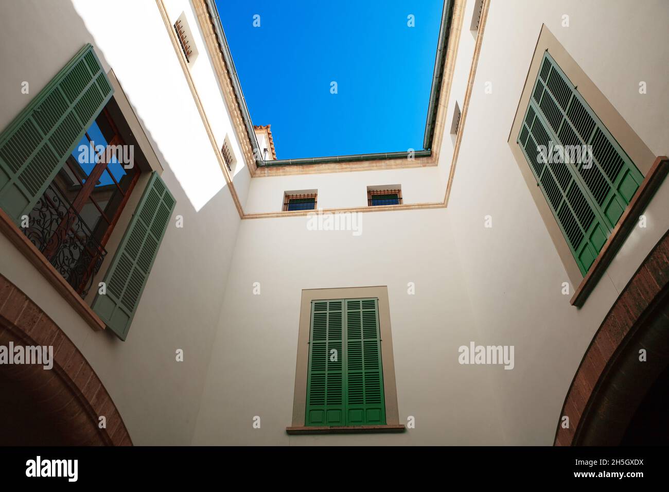 Blue sky above walls . Closed space architecture . Windows with green ...