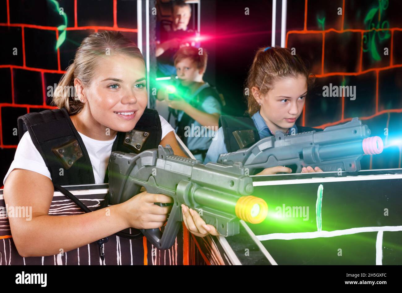 Girl with laser gun having fun on laser tag arena with her teen Stock ...