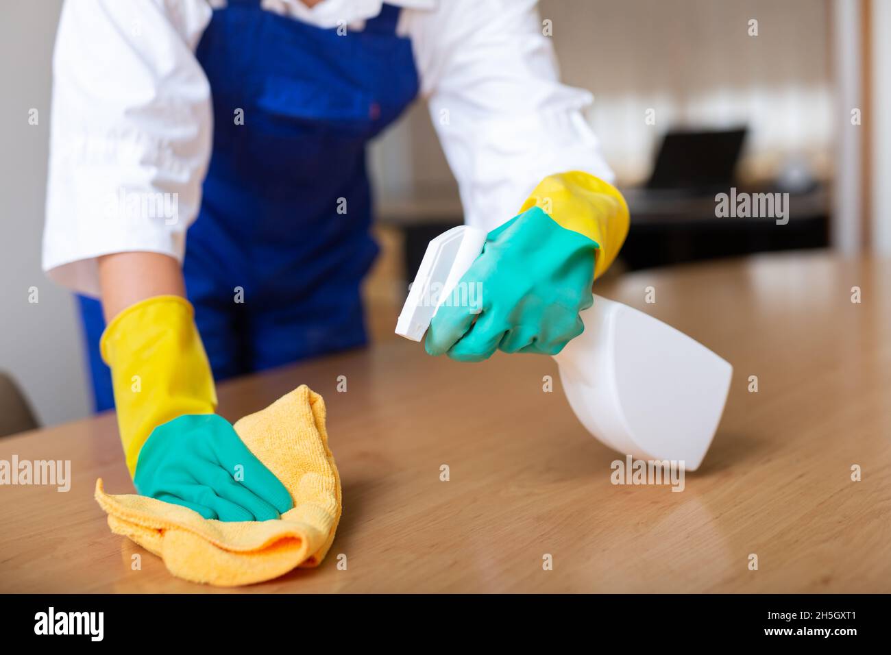 Image of gloved hands cleaning an office desk with a rag and detergents ...