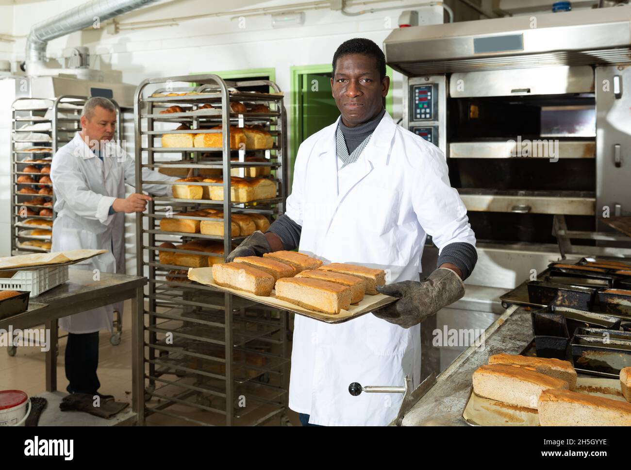 African-american baker spreads hot bread on a pallet Stock Photo - Alamy