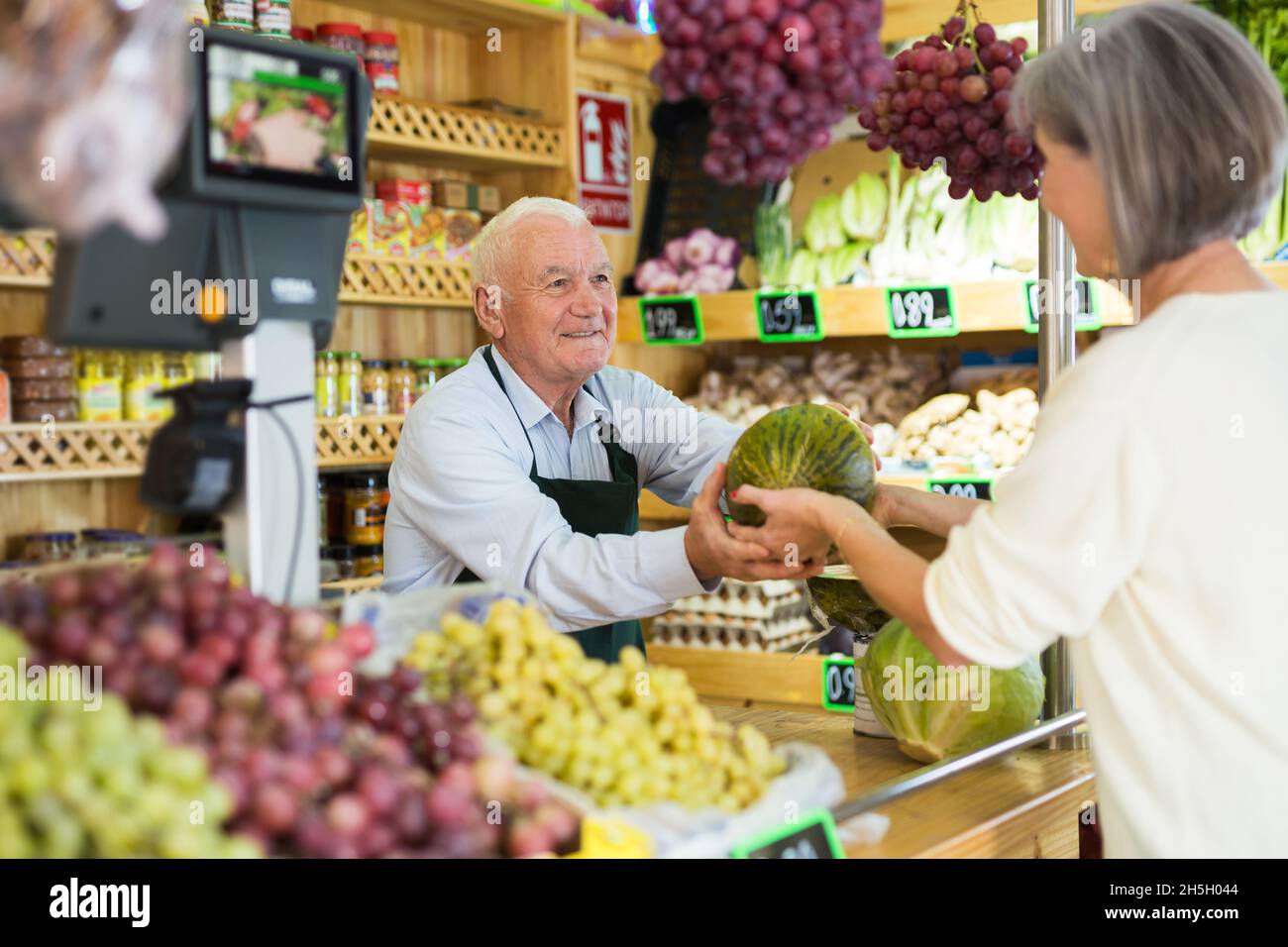 Senior cashier serving customer in greengrocer Stock Photo - Alamy