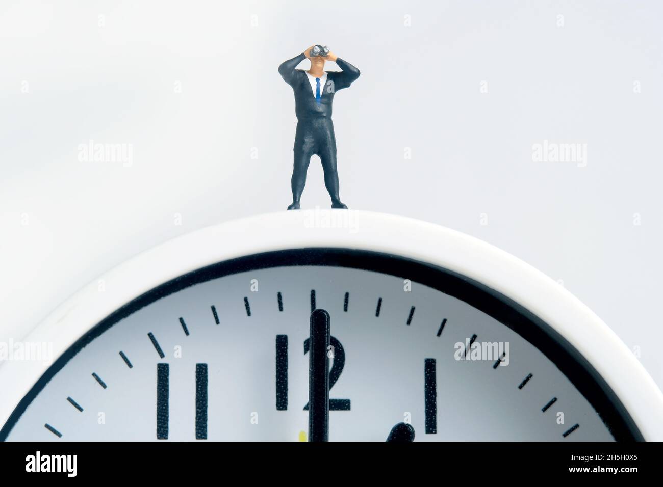 Businessmen using binoculars standing above clock. Miniature tiny ...