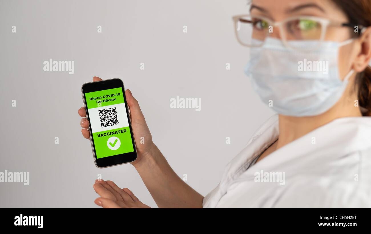 The doctor recommends vaccination and holds a smartphone with a QR code ...